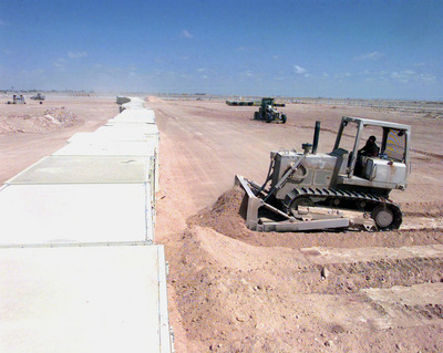 Metal shipping containers are positioned to form a security perimeter ...