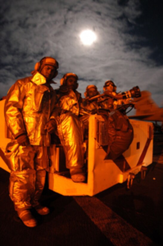 Firefighters stand next to a fire truck on the flight deck of the USS ...