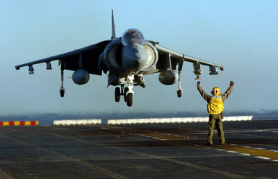 Petty Officer 1st Class Roberto Gonzales directs a Marine Corps AV-8B ...