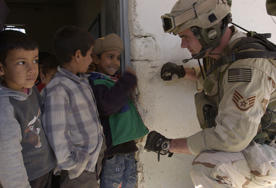 Air Force Staff Sgt. Kyle Luker talks with three boys at a school.
