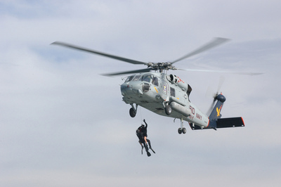 A Navy SH-60F Seahawk helicopter hoists two search and rescue swimmers ...
