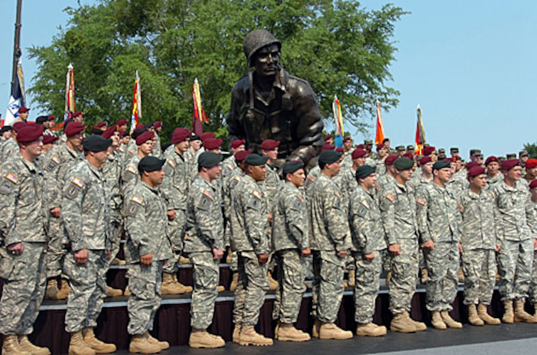 Paratroopers, soldiers, and airmen gather around the Iron Mike statue ...