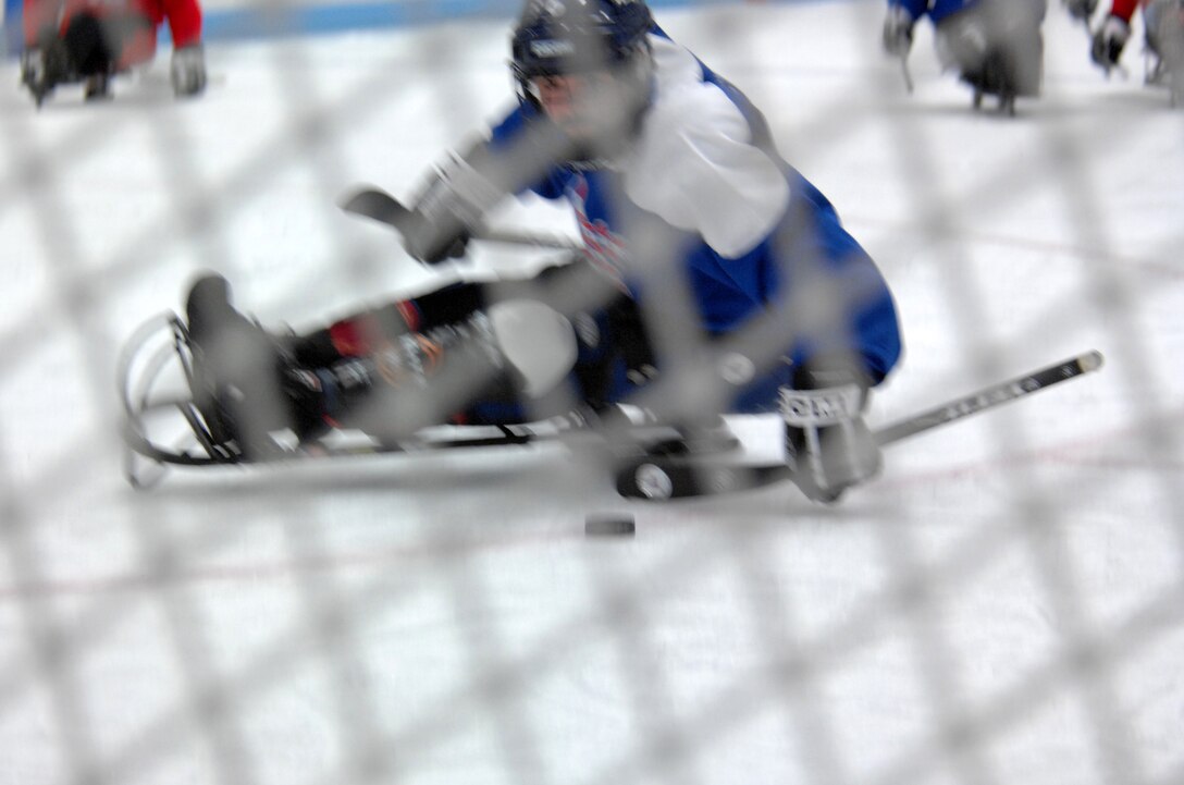 A disabled veteran shoots for a goal during a sled hockey game at the ...