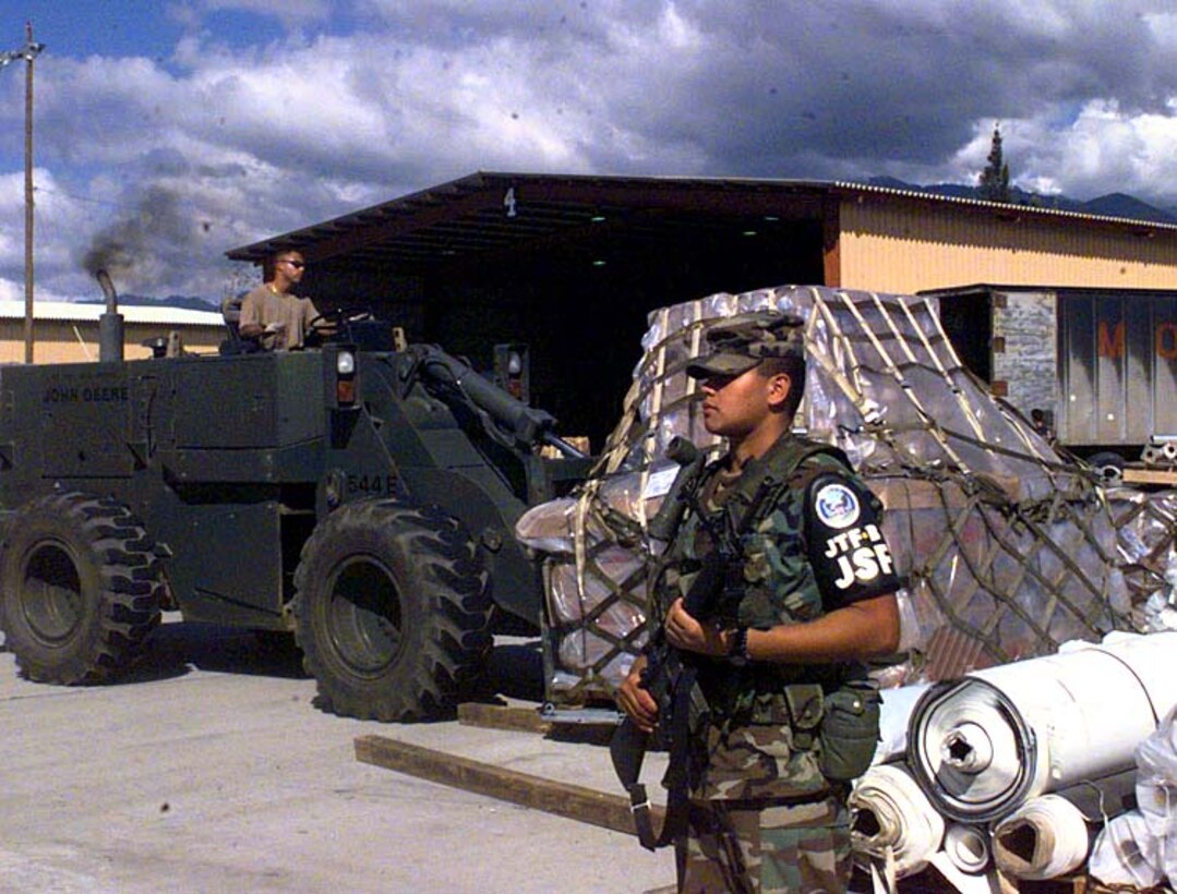 Pfc. Rafael Weyrauch stands guard over Hurricane Mitch relief supplies ...