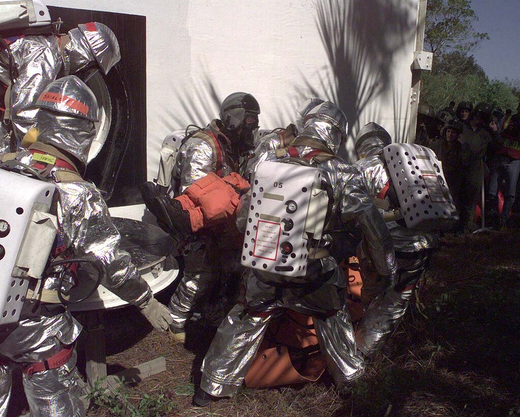 NASA firefighters extract an astronaut from a space shuttle mockup ...