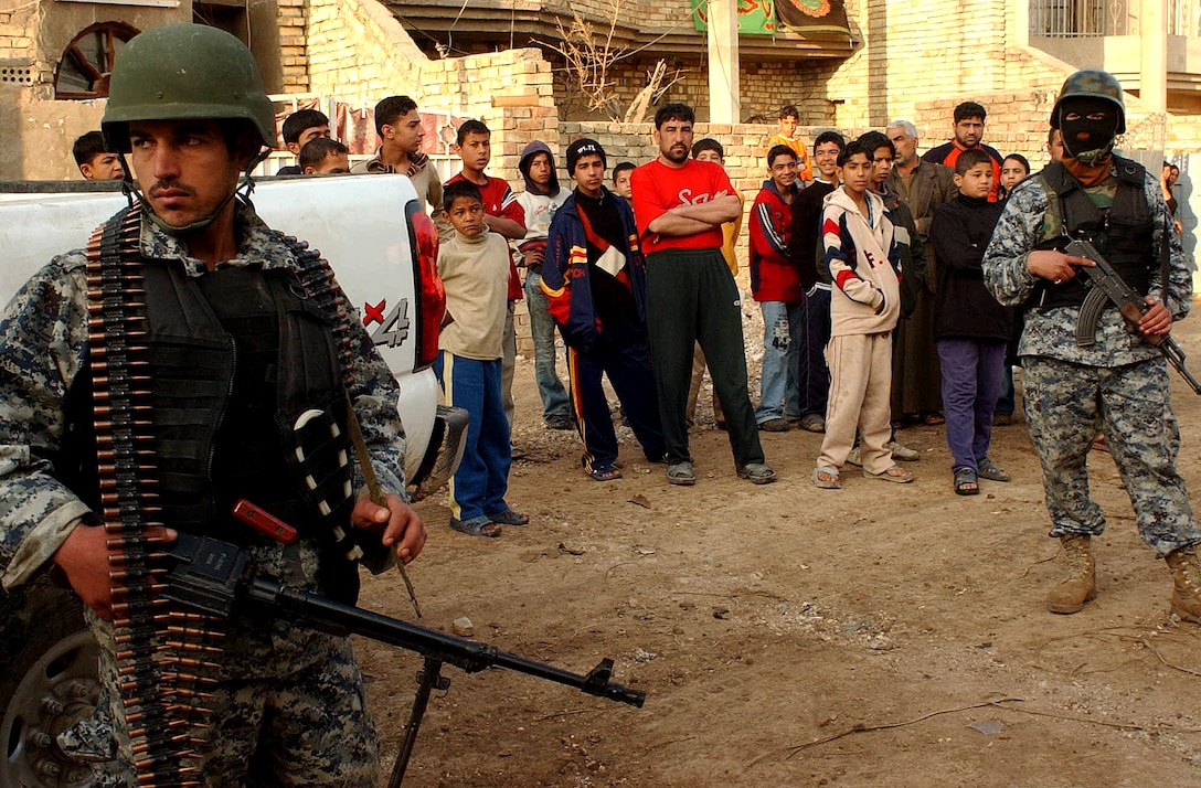 Iraqi National Police officers pull security outside a house during a ...