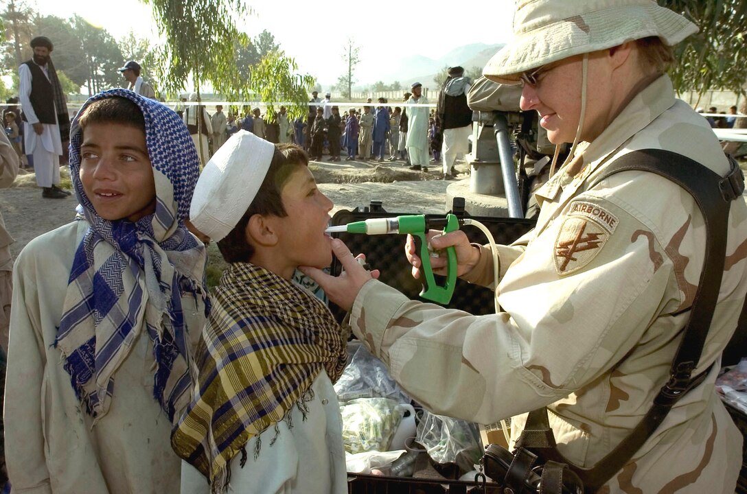 U.S. Army Capt. Lisa Yanity gives deworming medicine to a boy in Tere ...