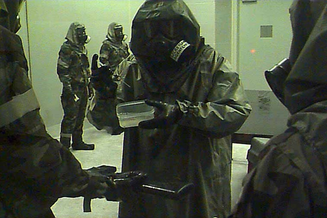 An agent handler carries a syringe full of nerve agent over a bowl of ...