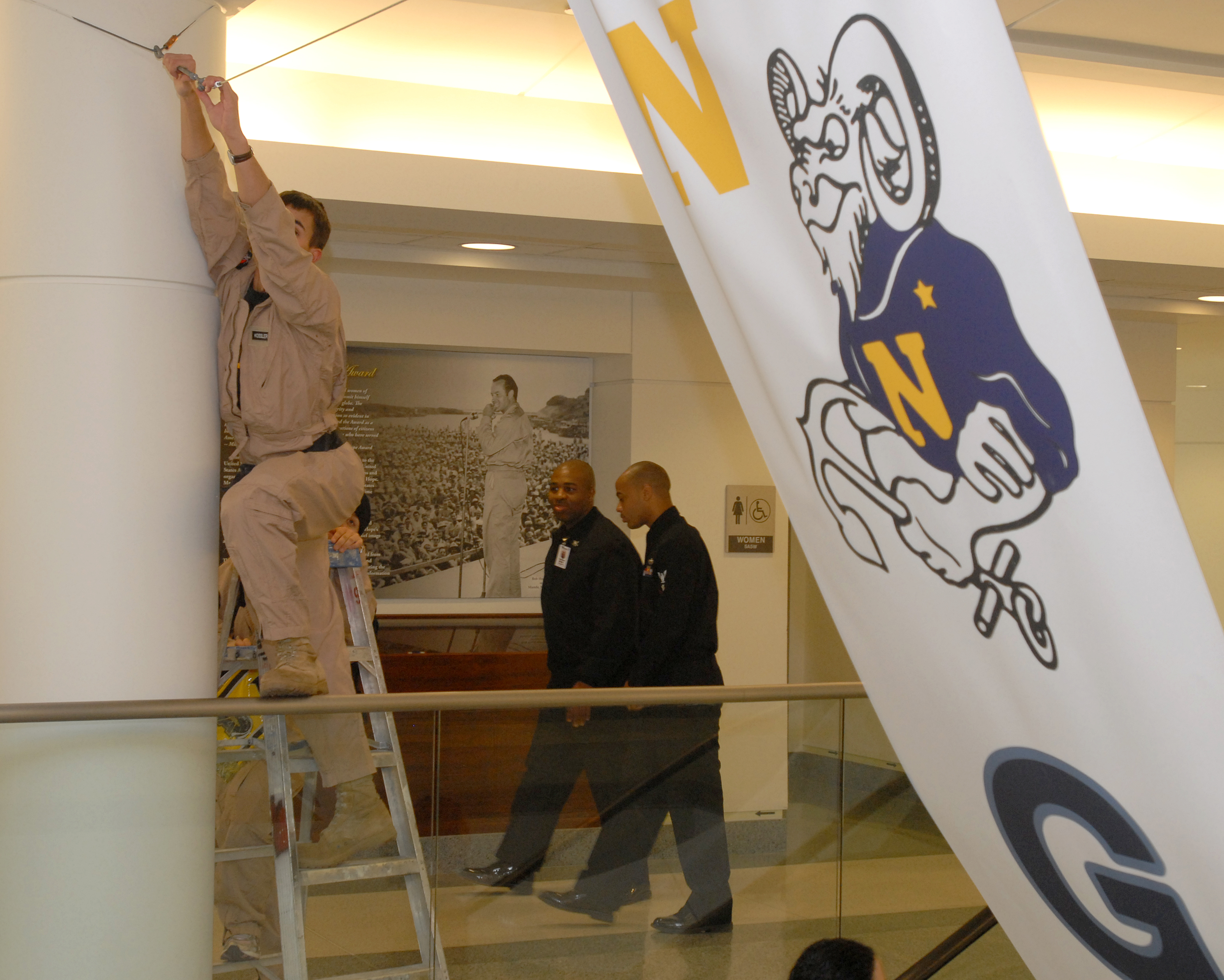 An Army cadet unrigs a banner that reads “GO NAVY! BEAT ARMY” while ...