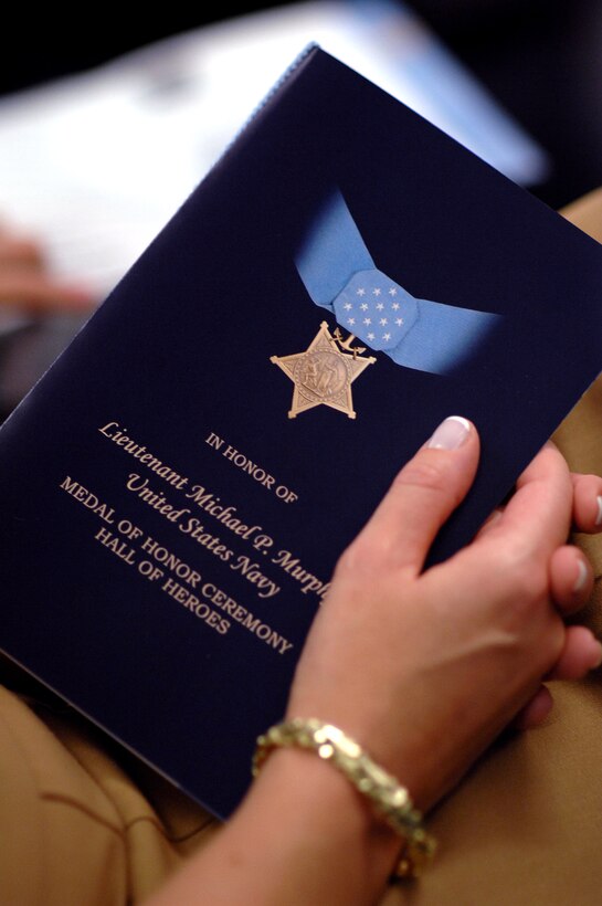 An attendee holds the Medal of Honor award program during a ceremony ...