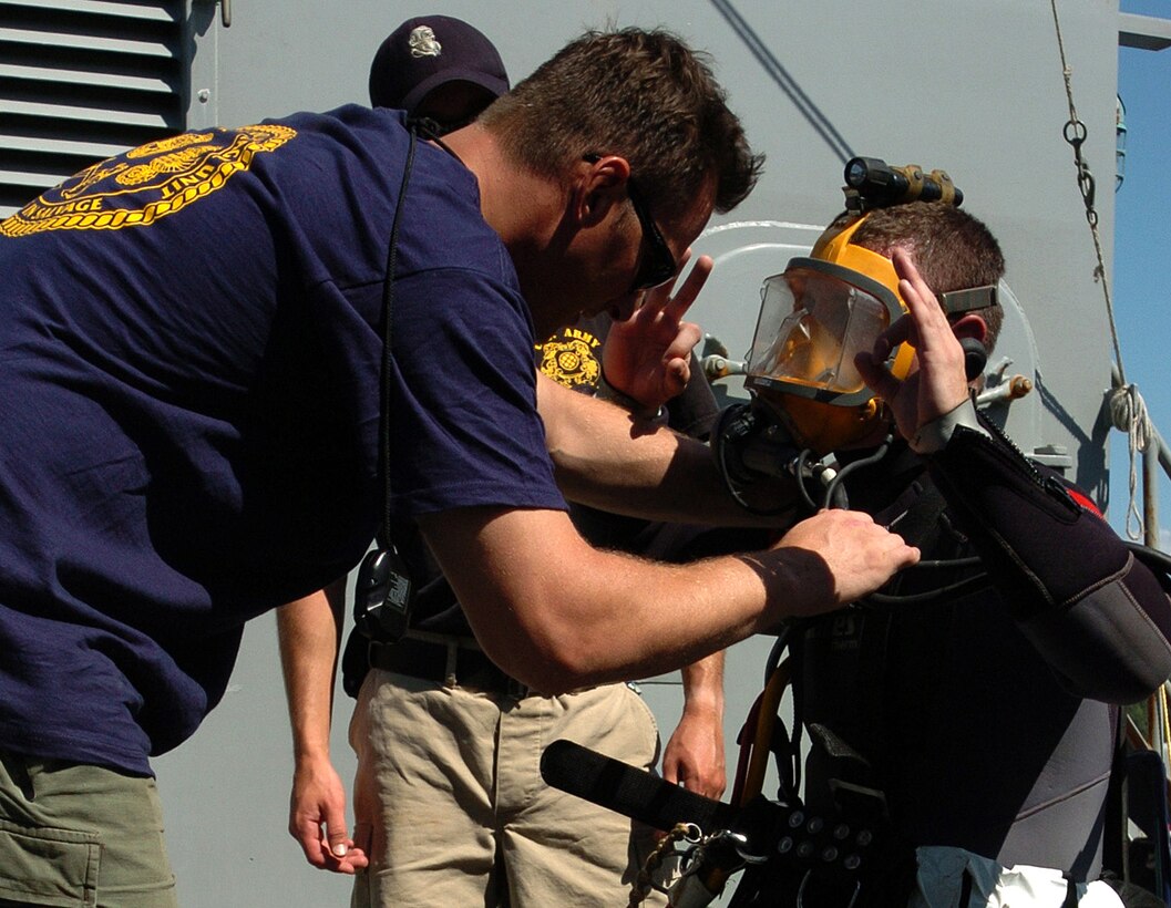 Navy diver Petty Officer 2nd Class William F. Stetson III, right, gives ...