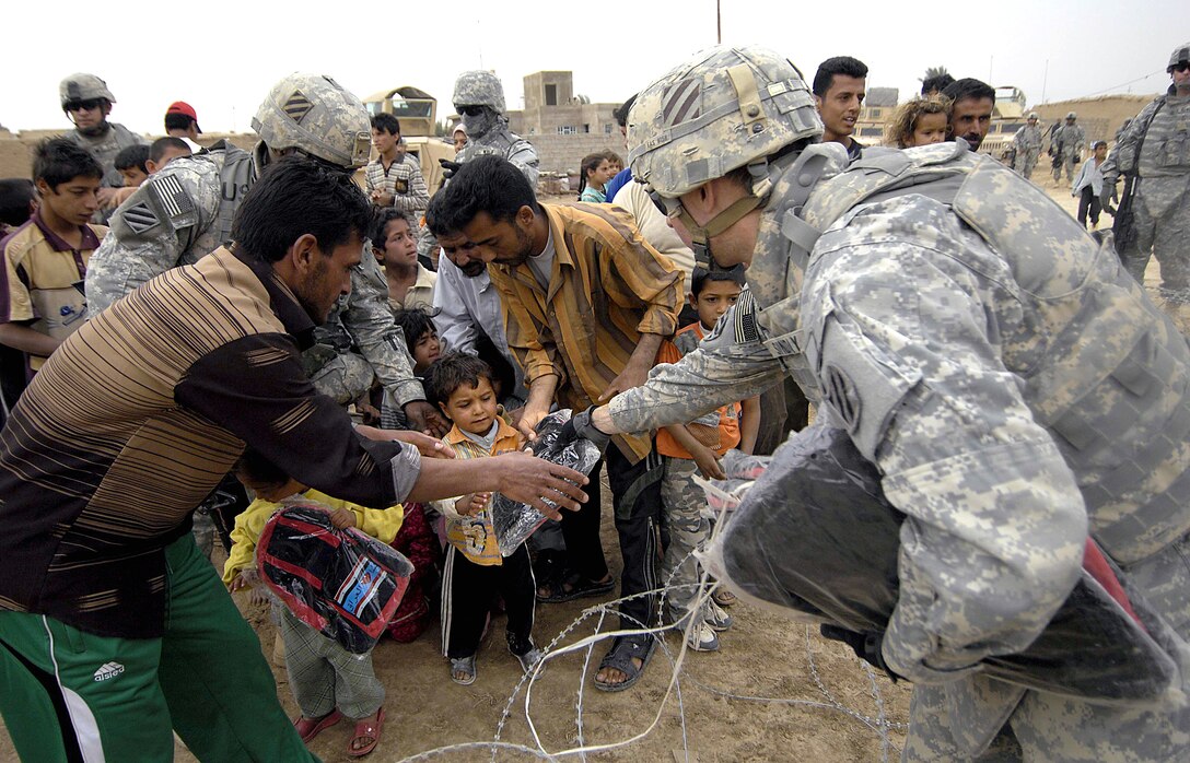 U.S. Army soldiers hand out supplies to villagers during a medical ...