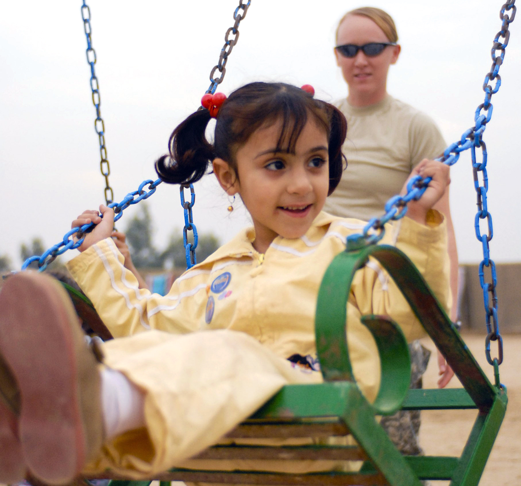 U.S. Army Sgt. Shannon LeMaster pushes a girl on a swing during a troop ...