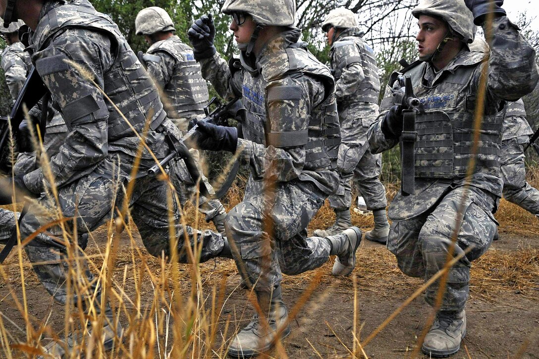 Air Force basic trainees in body armor use hand signals as they take a ...