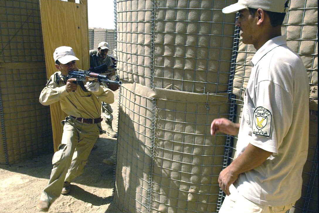 An Iraqi SWAT team officer moves to secure a non-combatant during close ...