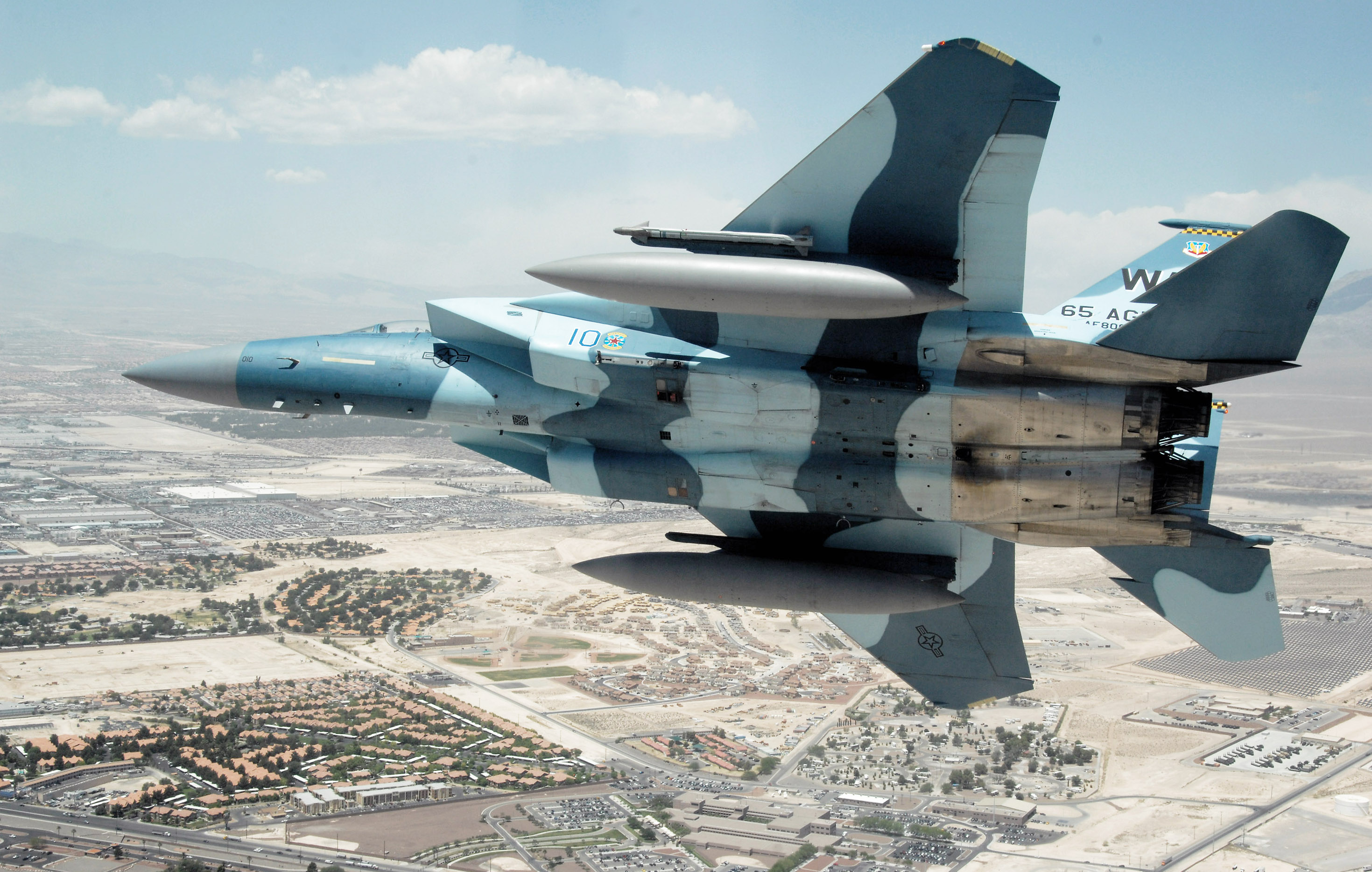 An F-15 Eagle in the "aggressor" paint scheme pitches out for landing ...