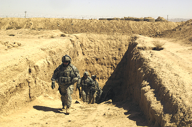 U.S. Army Soldiers walk out of an assumed trash pit or man-made bunker ...