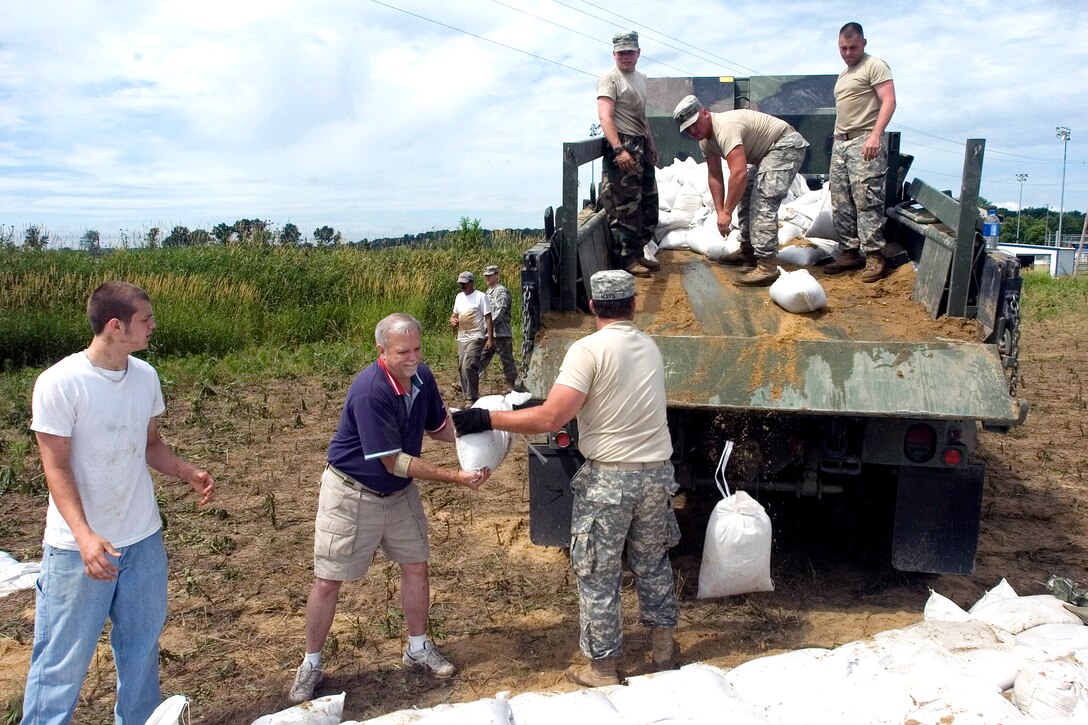 Missouri U.S. Army National Guard members and local civilians unload a ...