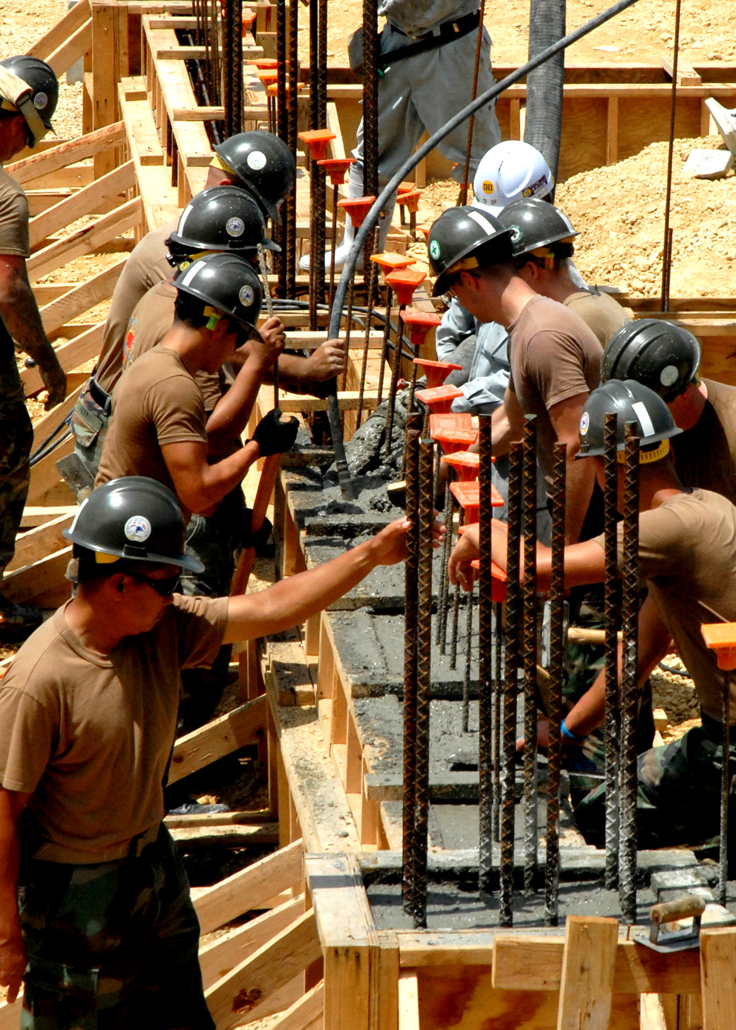 U.S. Navy Seabees assigned to Naval Mobile Construction Battalion 5 operate a concrete vibrator ...
