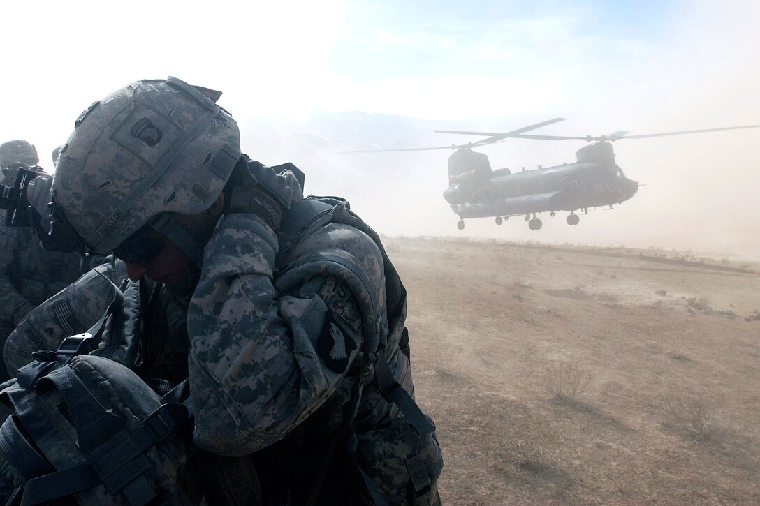 U.S. Army soldiers shield themselves from flying debris and dusty winds ...