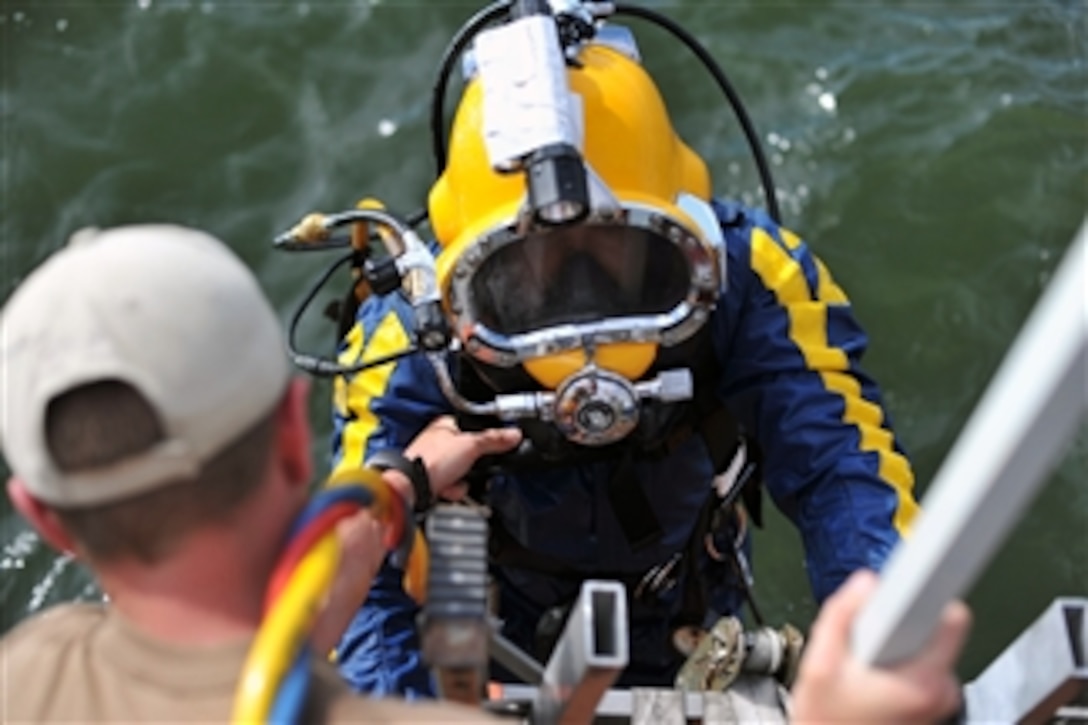 Petty Officer 1st Class Eric Riggenbach climbs aboard a rescue boat ...