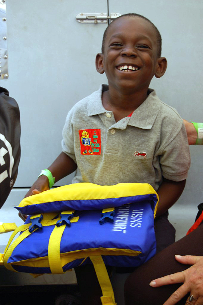 A Haitian child removes his life vest after being transported to the ...