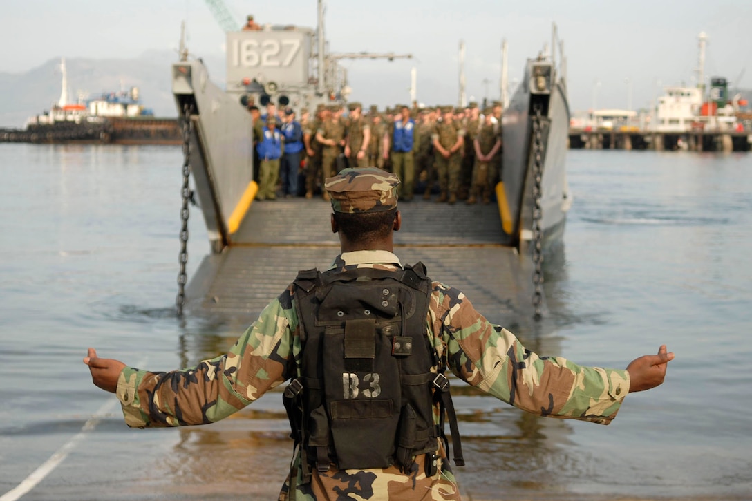 A U.S. Navy sailor assigned to Beach Master Unit 1 directs Landing ...