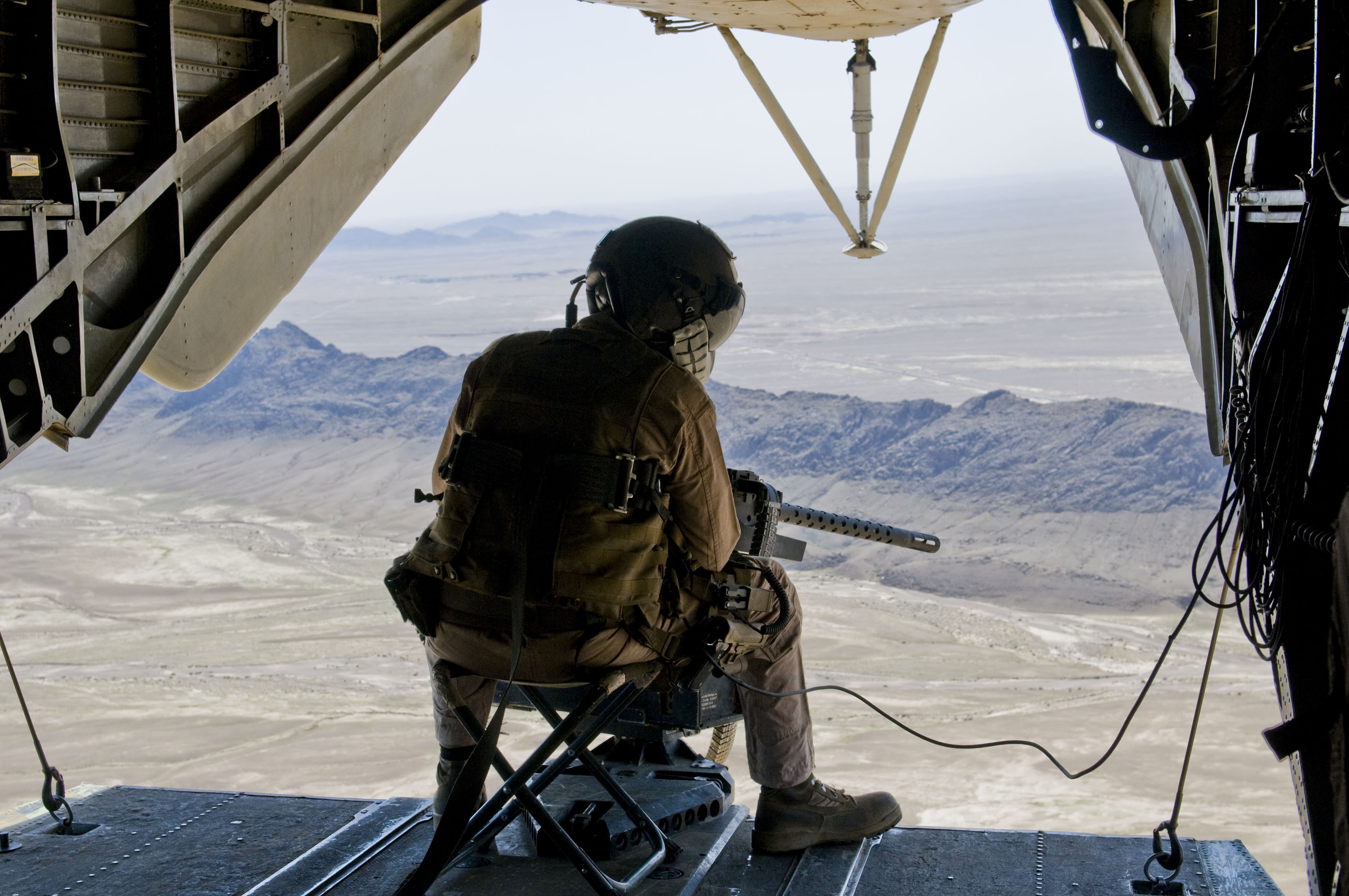 A tail-gunner in a CH-53 Sea Stallion checks the terrain for anything ...