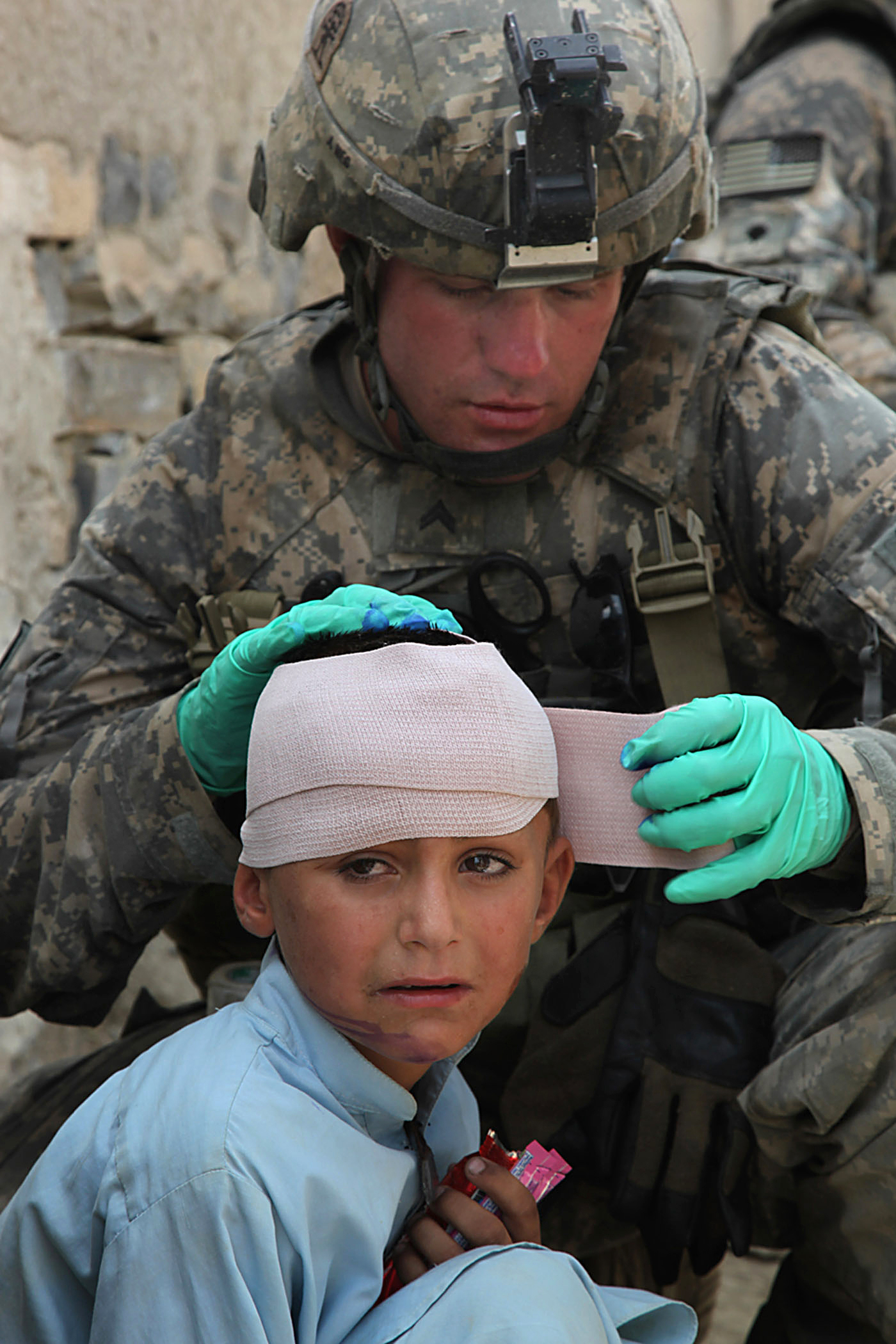 U.S. Army Cpl. James Daoust provides medical care to an Afghan boy ...