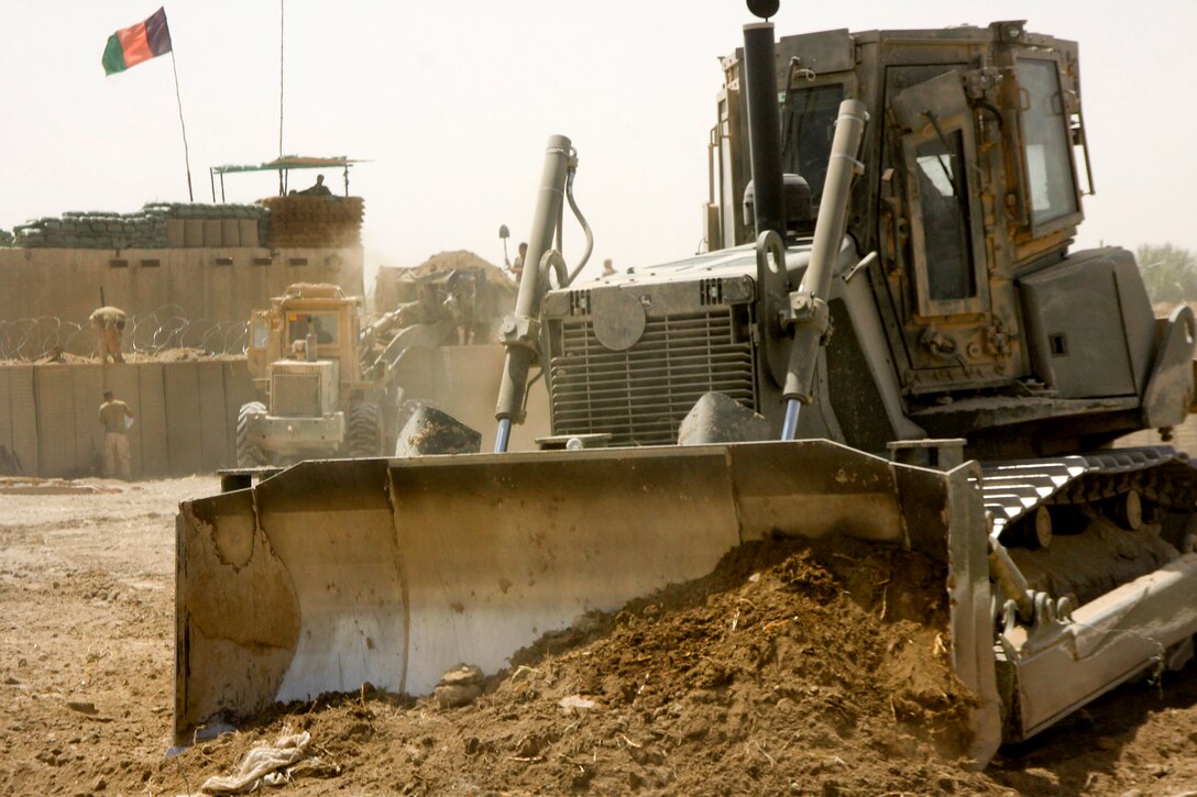 U.S. Marines use heavy equipment to flatten the ground to build new ...