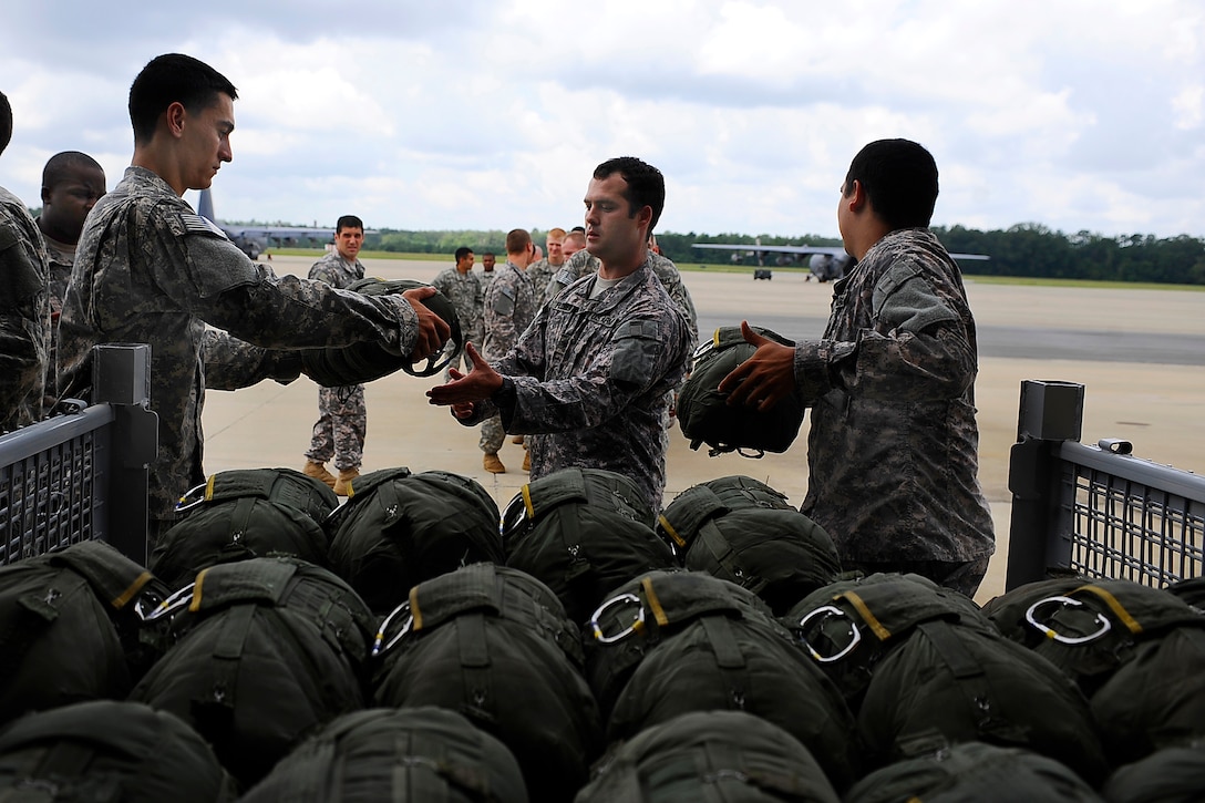 U.S. Army Rangers hand out reserve parachutes before a mass tactical ...