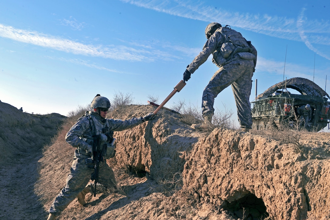 U.S. Army Cpl. David Tyrpin, left, takes an explosives detection wand ...