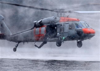 A U.S. Navy search and rescue aircrewman hoists into an MH-60S Seahawk ...