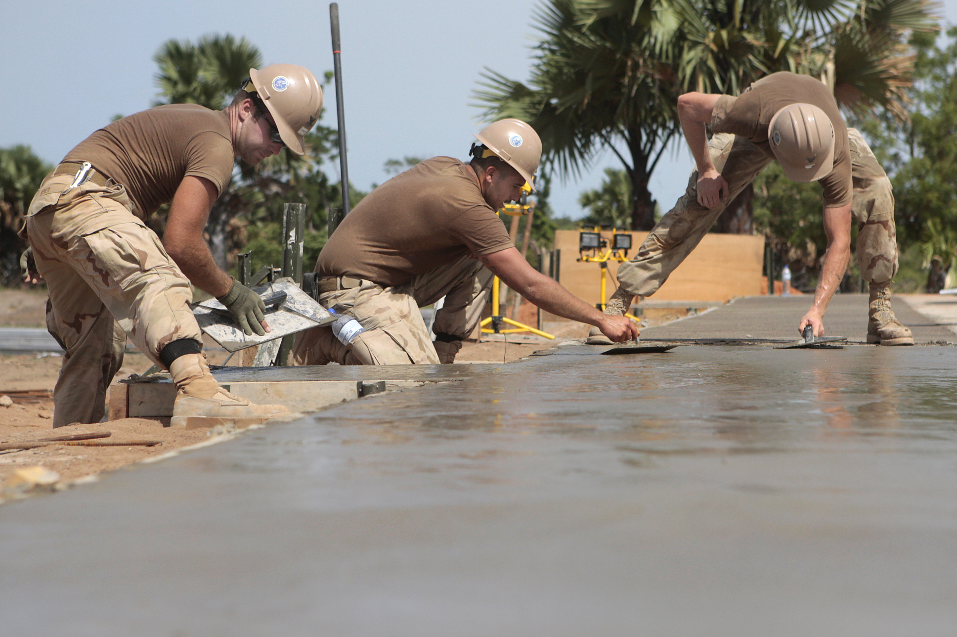 U.S. Marines smooth out cement that will be the foundation for a school ...