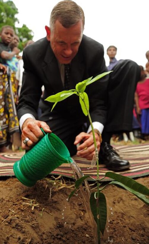 U.S. Navy Capt. Mark Sparling plants and waters a memorial mango tree ...