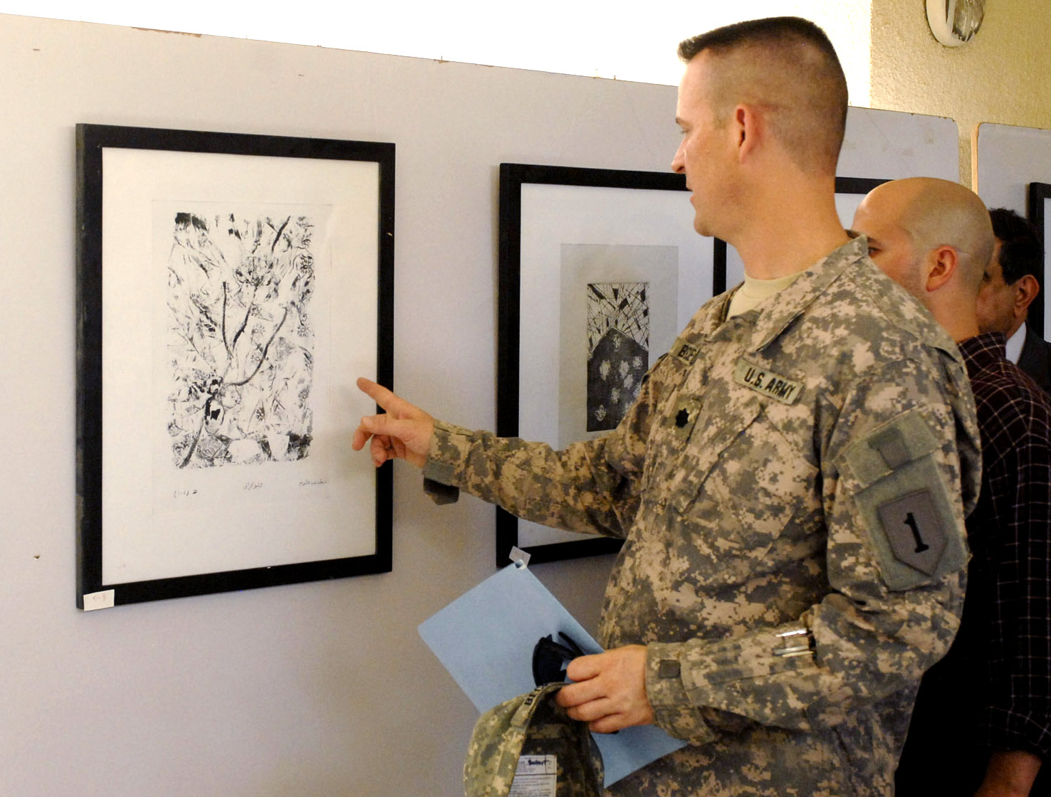 Army Lt. Col Christopher Beckert looks at works of art created by ...