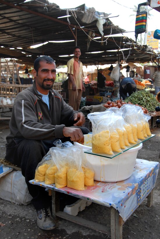 An Iraqi vendor bags corn meal for sale at a market in Mahawil, Iraq ...