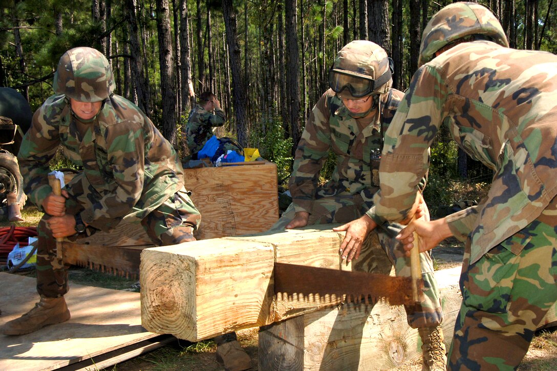 U.S. Navy sailors cut wood to build a timber tower during a training ...