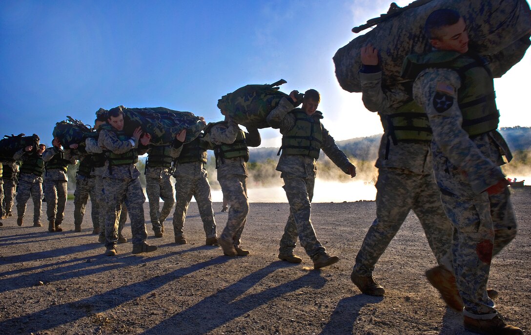 U.S. Army soldiers carry their poncho-rafts to an awaiting CH-47 ...
