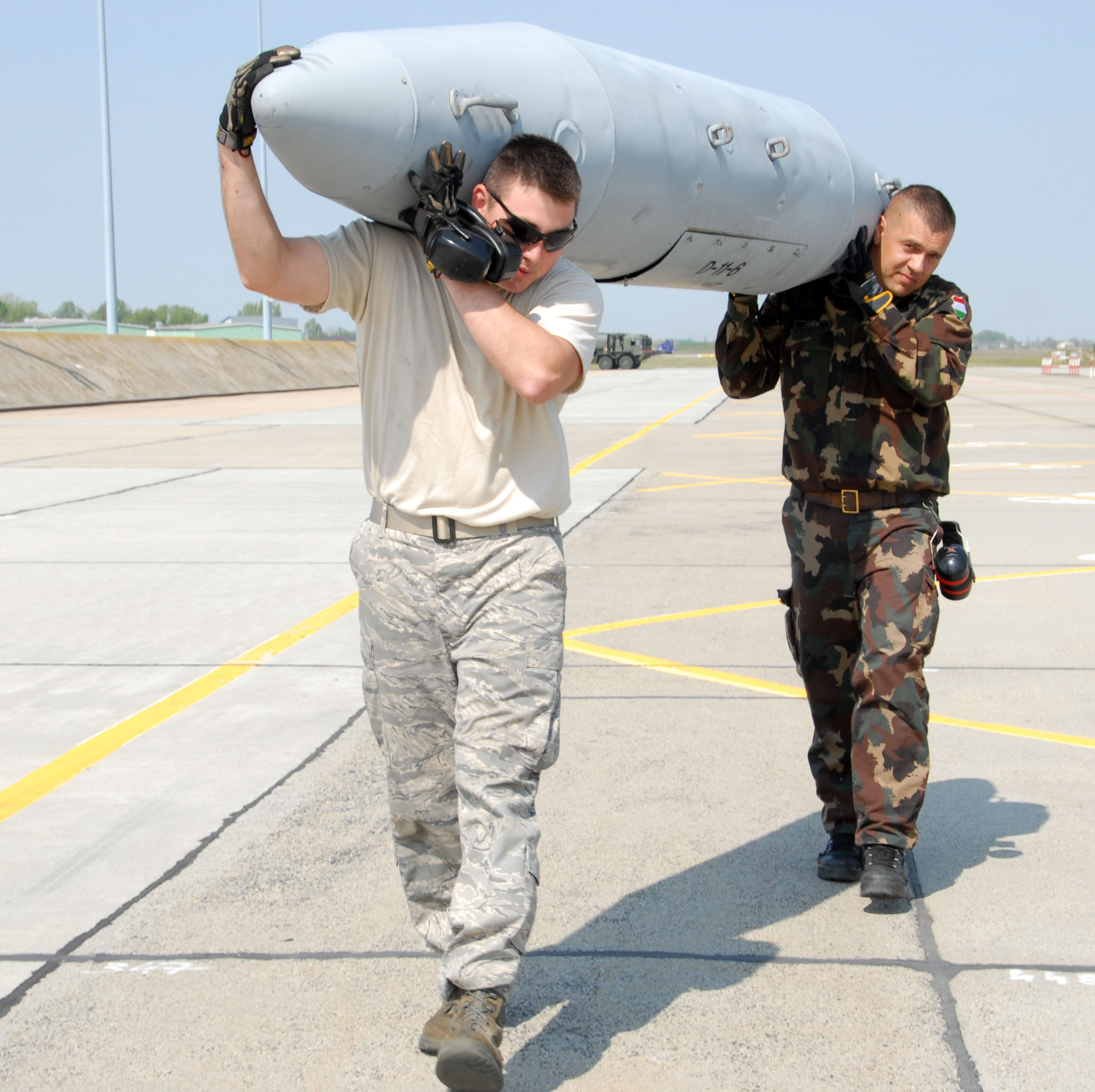 Staff Sgt. Barlau and a Hungarian Air Force maintainer carry an F-16 ...