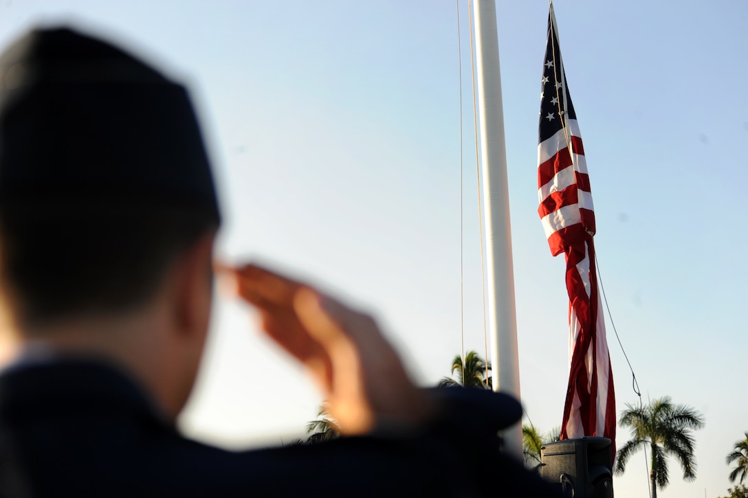A U.S. Air Force airman salutes while the U.S. flag is raised at the ...
