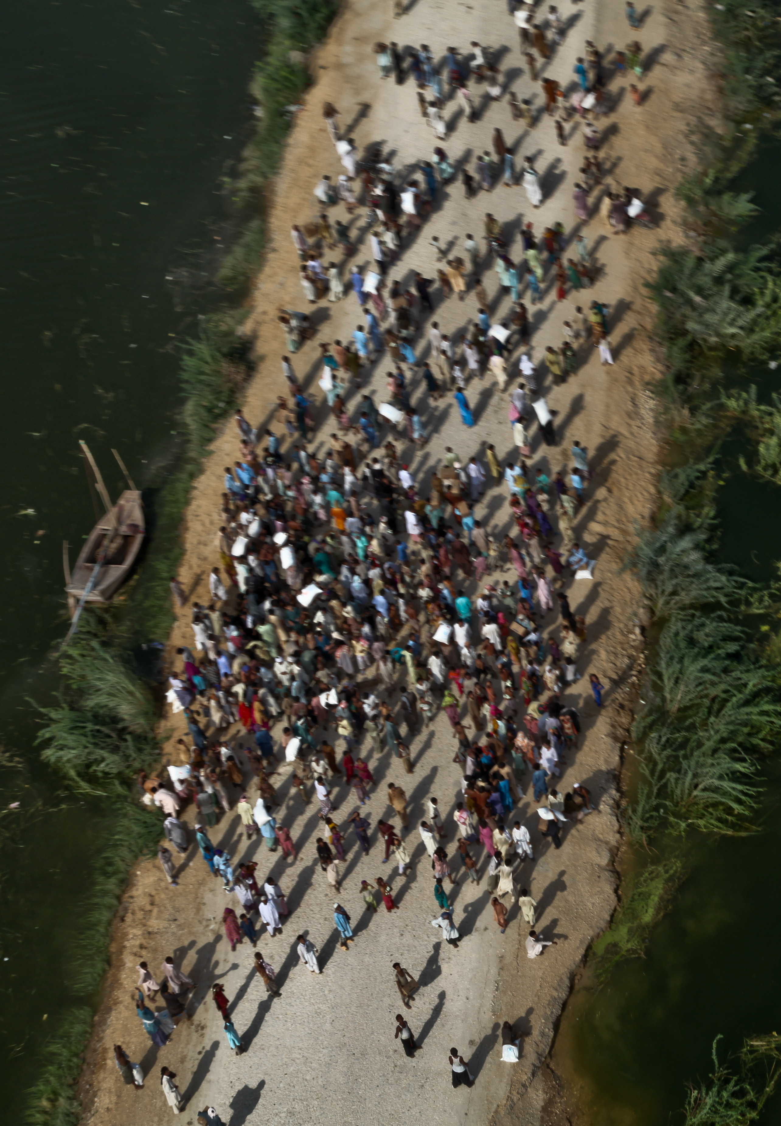 Pakistani flood victims gather on a road surrounded by flood waters in ...