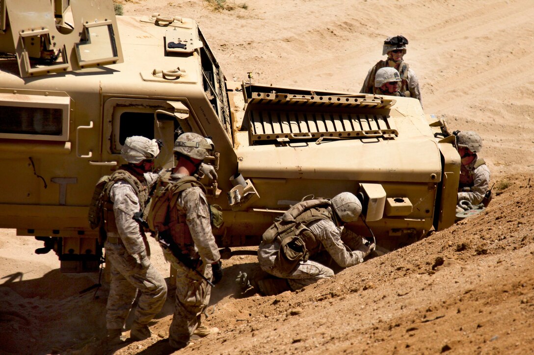 U.S. Marines dig out dirt to connect chains to a mine-resistant, ambush ...