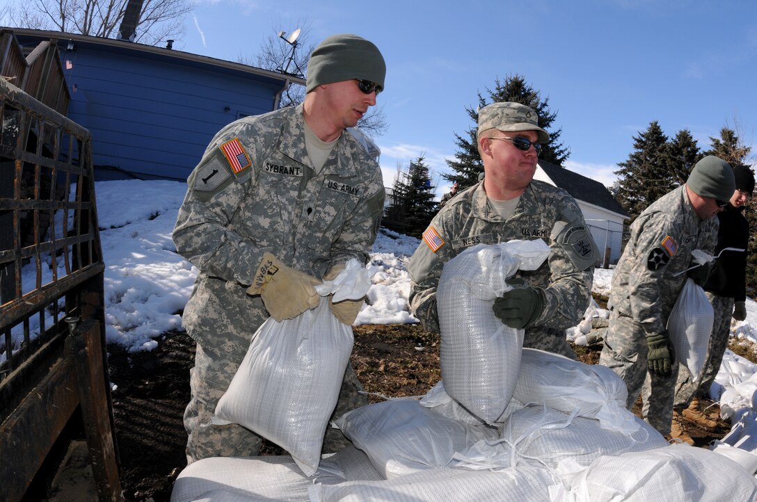 U.S. Army Spc. Tim Sybrant, left, passes sandbags to Pfc. Scott Ness ...
