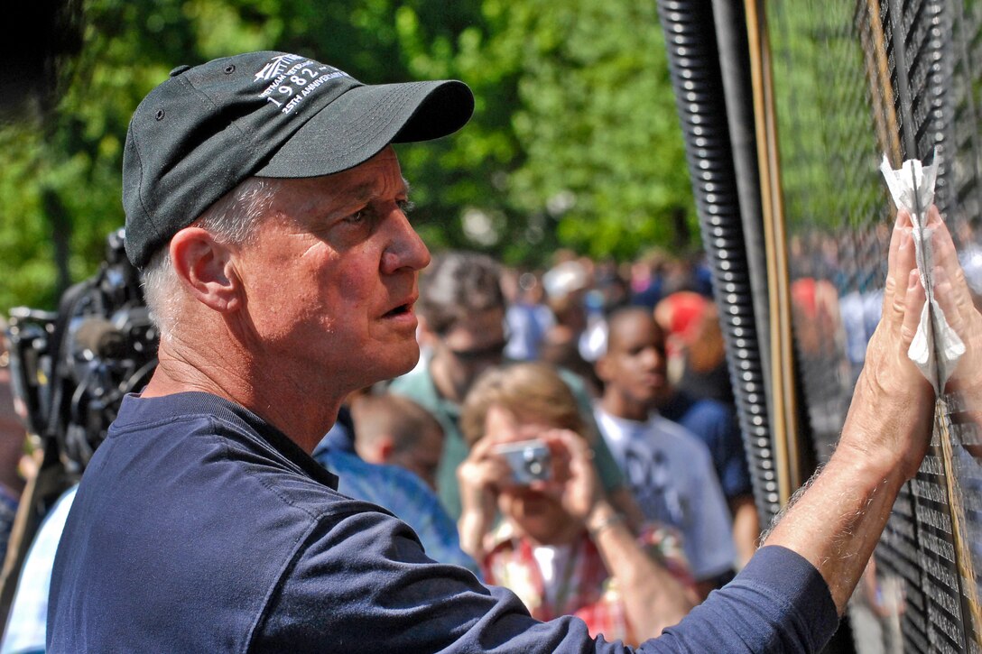 Expert stoneworker James Lee cleans the work after engraving the name ...