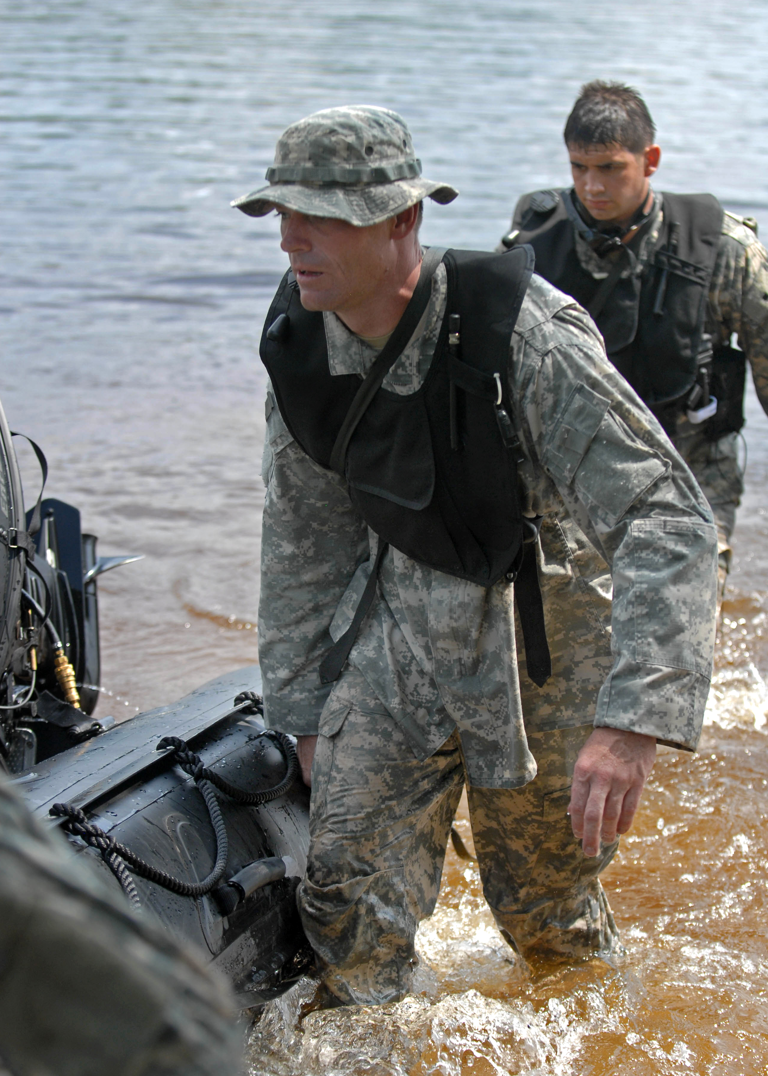 U.S. Army soldiers carry their zodiac boat to shore to conduct an After ...