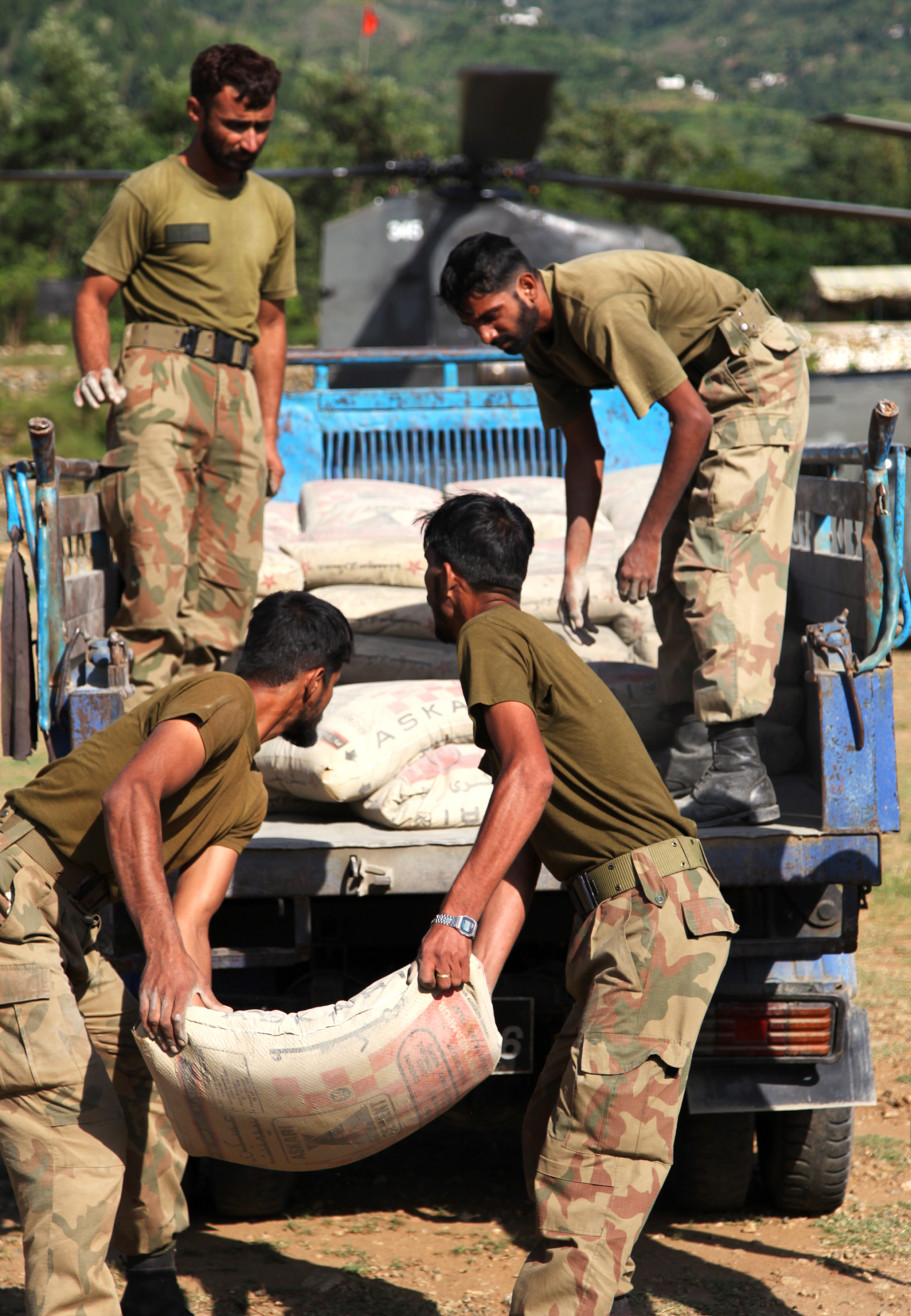 Pakistani soldiers load bags of concrete onto a truck in Khyber ...