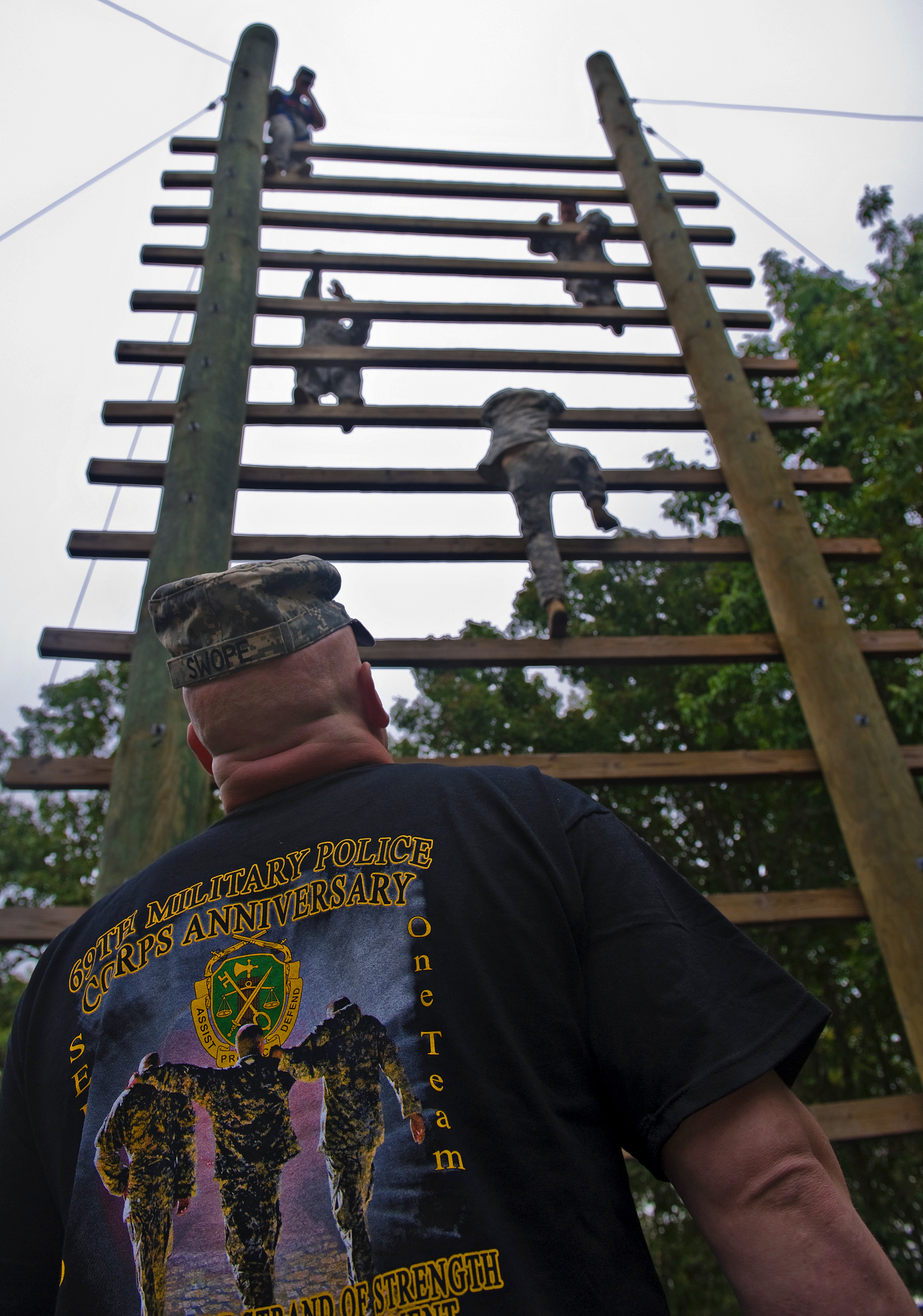 An instructor looks on as U.S. Army soldiers climb up and over a ...