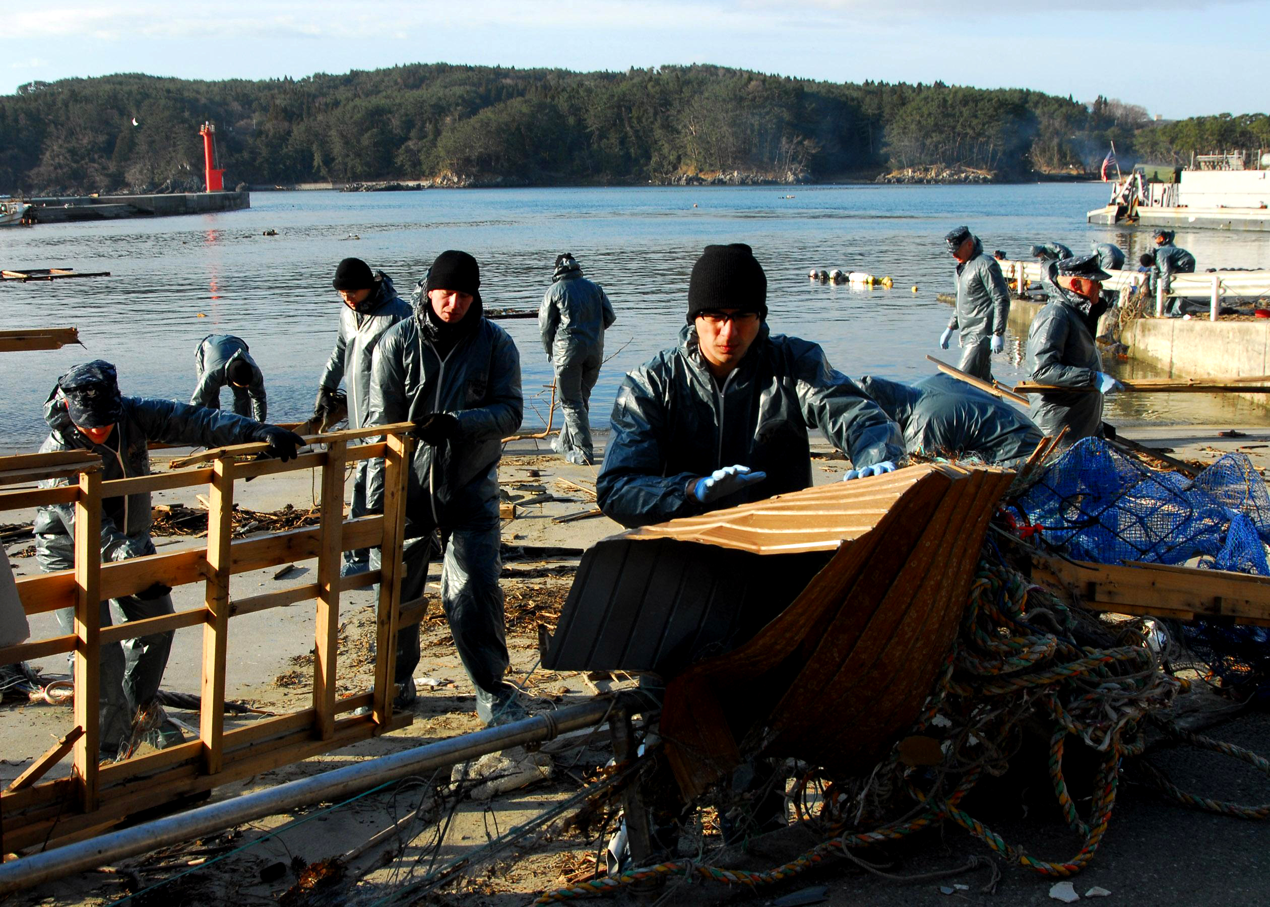 U.S. Navy sailors clean up debris from a harbor in Oshima Island, Japan ...