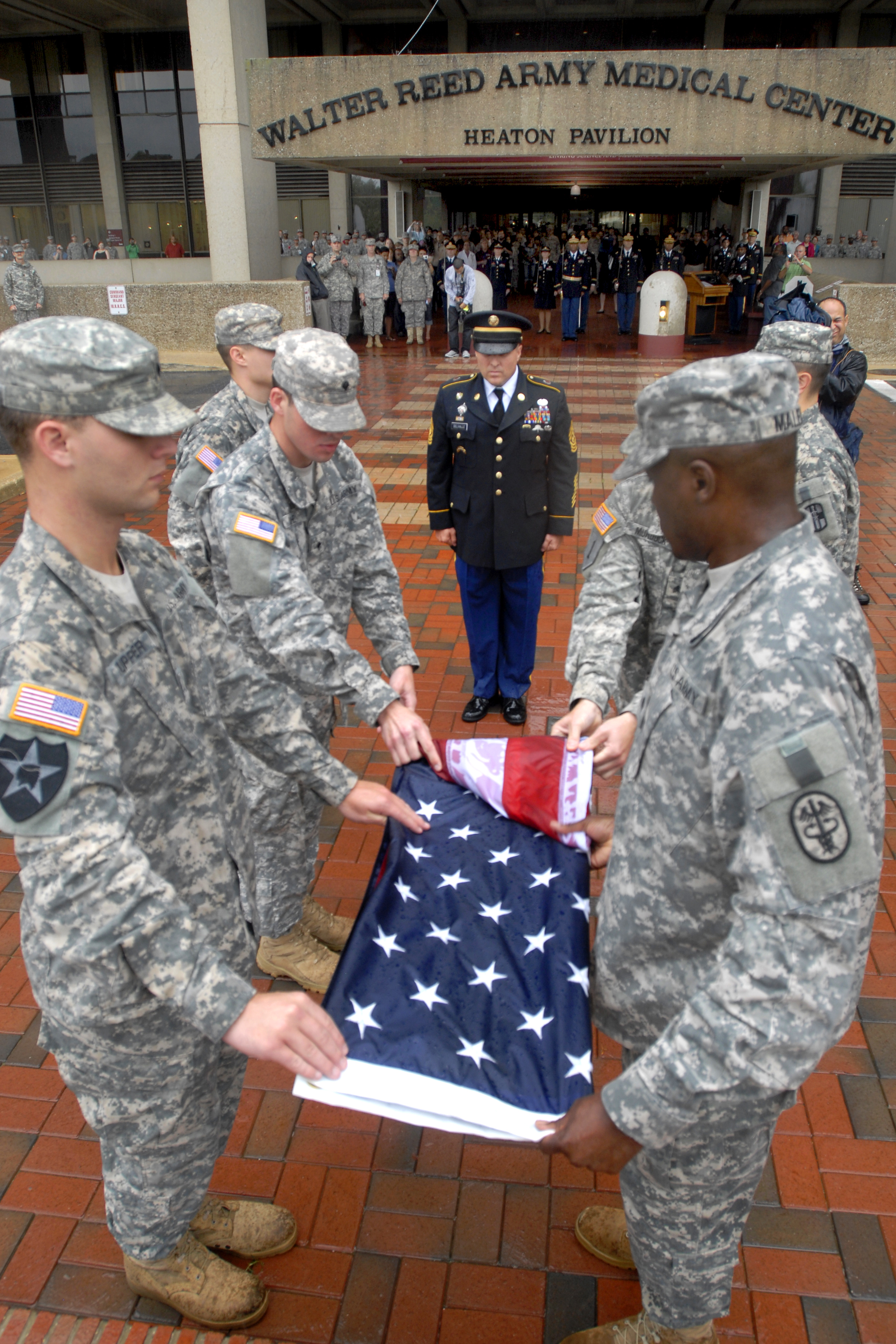 Members of the honor guard fold the U.S. flag after it was lowered for ...
